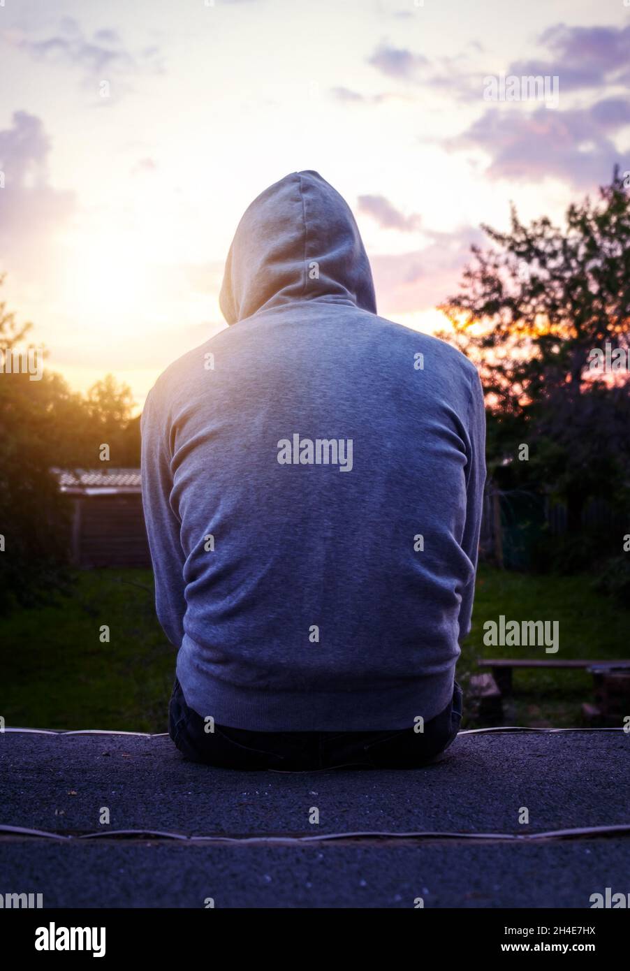 Rear View of a Lonely Young Man in a Hoodie sit on the Sunset ...