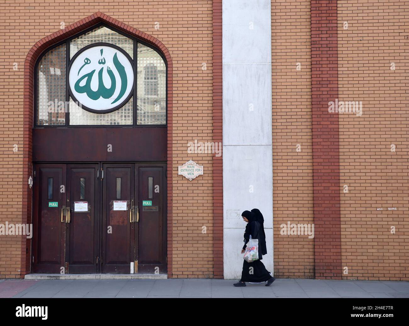 Muslim women walk past a closed-down East London Mosque in east London ...