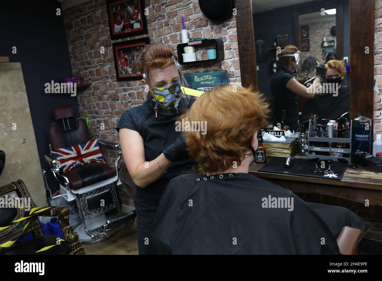 A hair stylist wearing Personal Protective Equipment (PPE) at work at ...