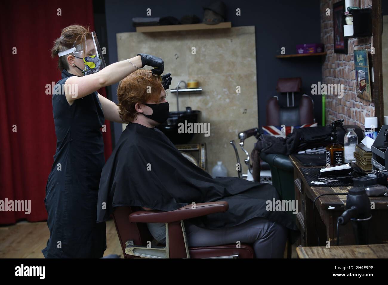A hair stylist wearing Personal Protective Equipment (PPE) at work at ...