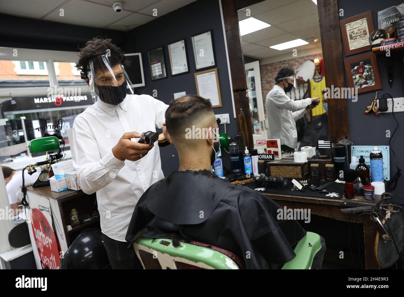 A hair stylist wearing Personal Protective Equipment (PPE) at work at ...
