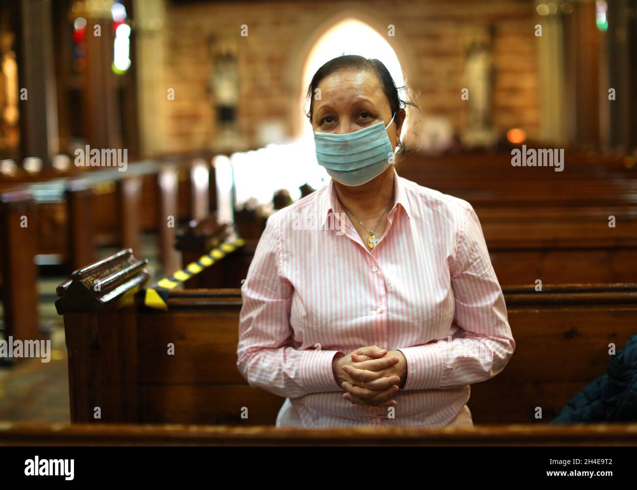 A churchgoer prays wearing a face mask as Personal Protective Equipment ...