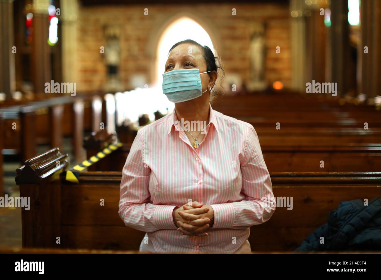 A churchgoer prays wearing a face mask as Personal Protective Equipment ...