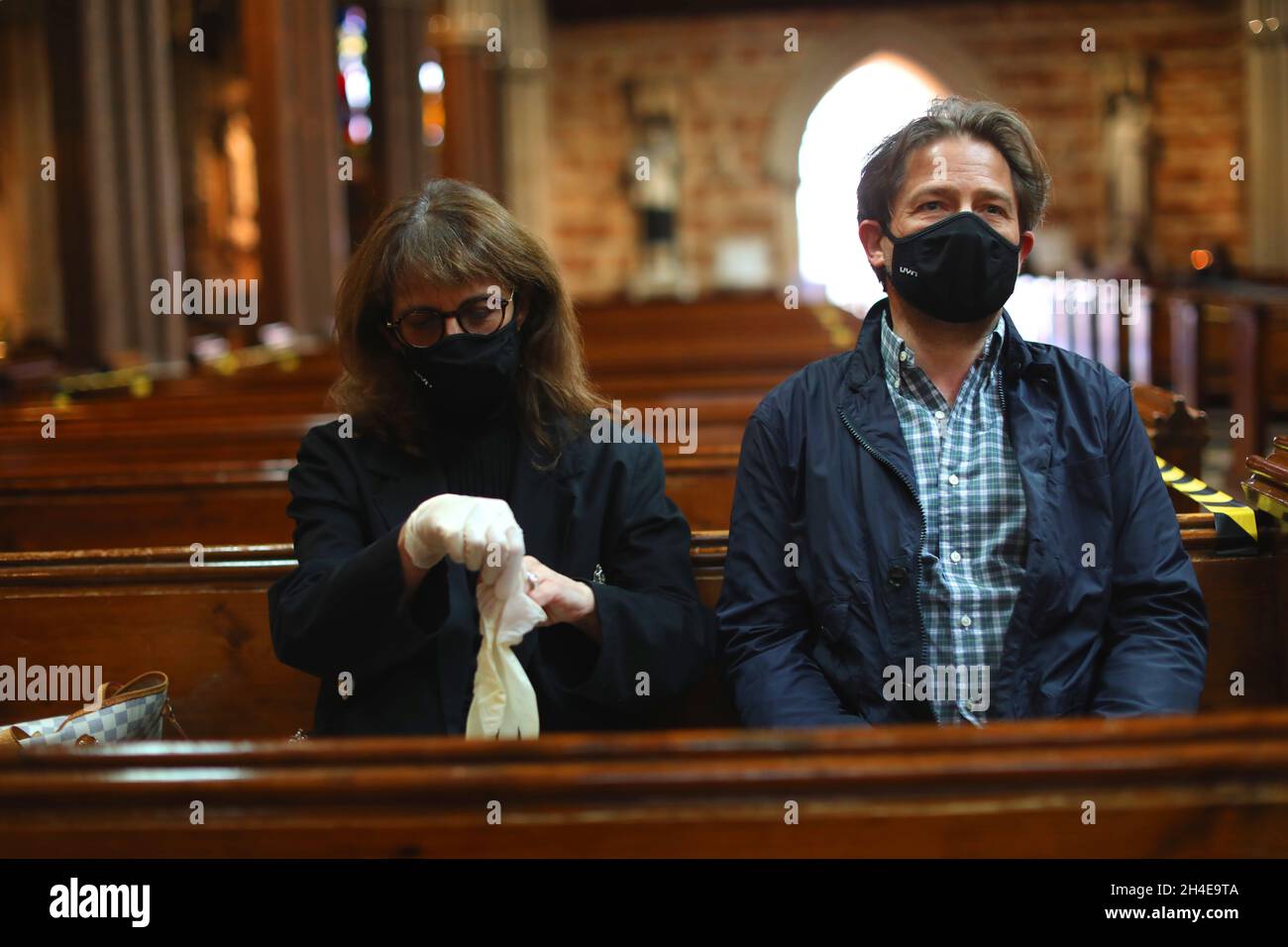 A couple of churchgoers wearing a face mask and plastic gloves as ...