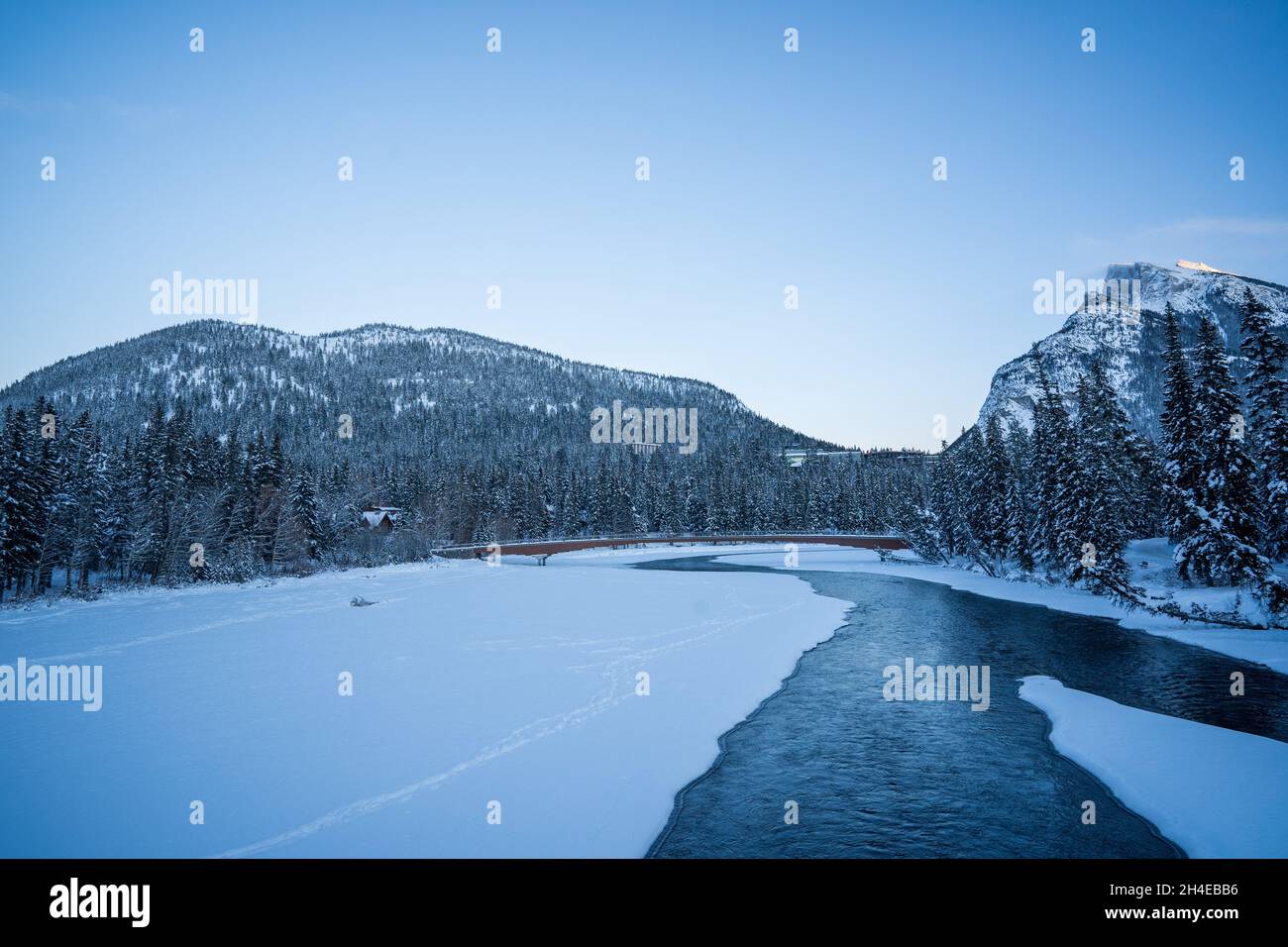 Chilling view of a frozen river and forest landscape under a clear blue ...