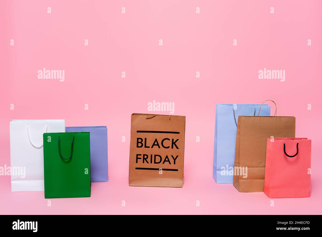 multicolored shopping bags and black friday lettering on pink ...