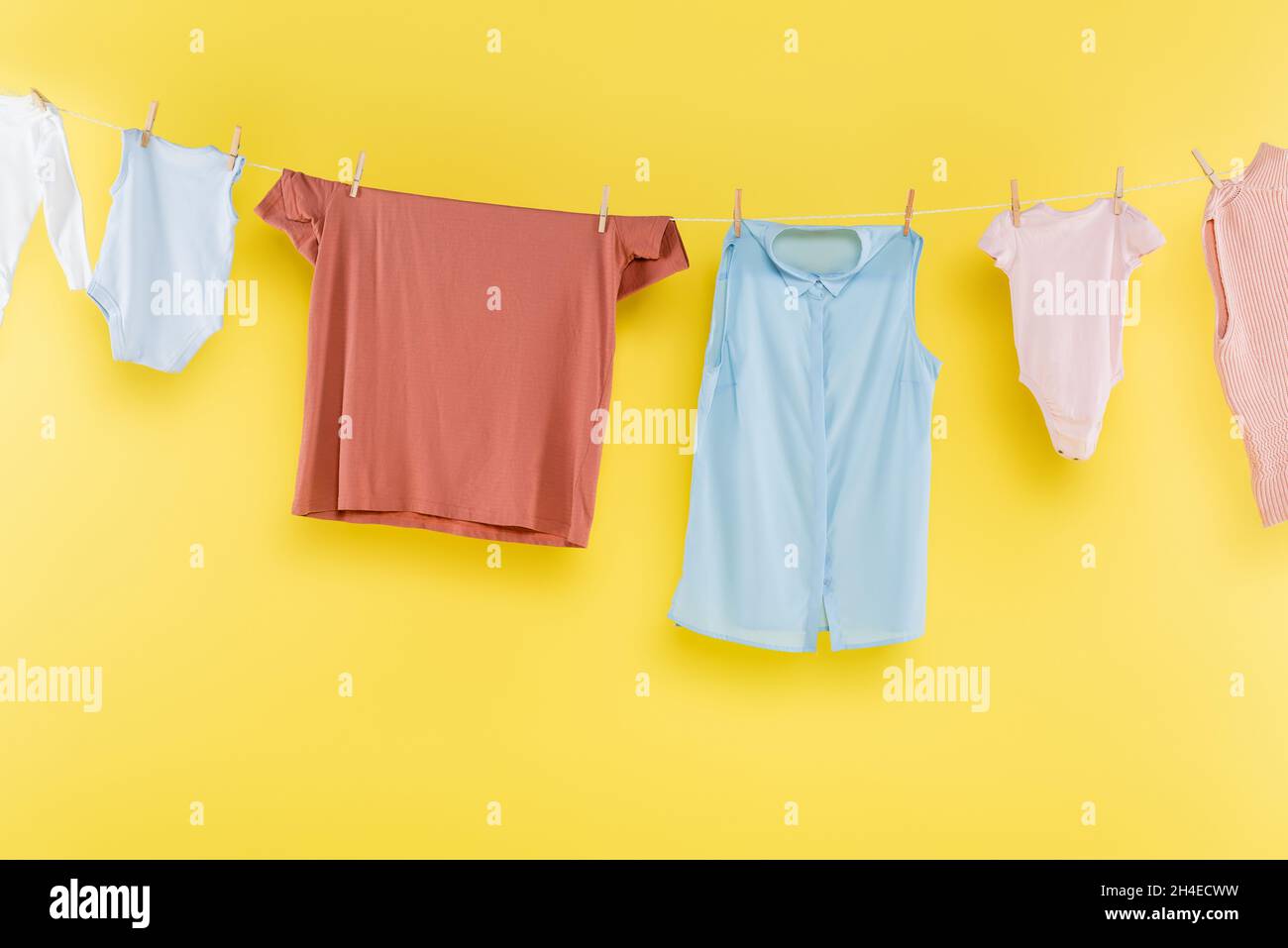 different clothes hanging on rope on yellow background Stock Photo - Alamy