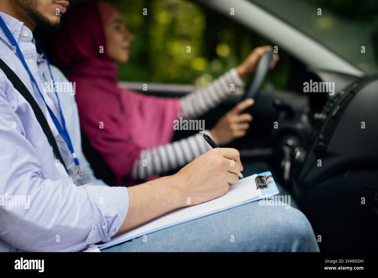 Driving School Concept. Male instructor examining muslim lady driver ...