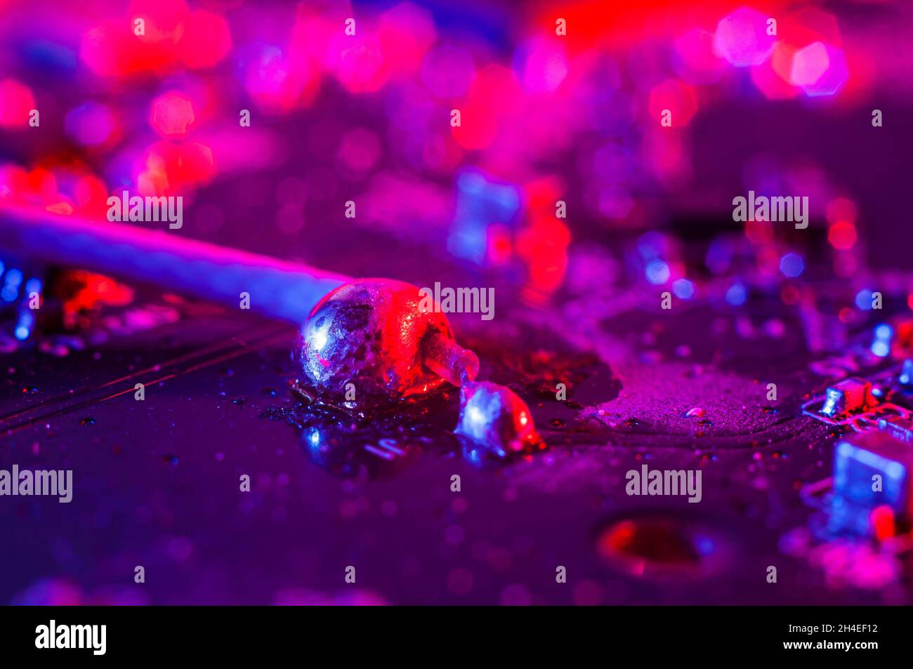 Wire soldered to old electronic board close-up, red and blue lighting ...