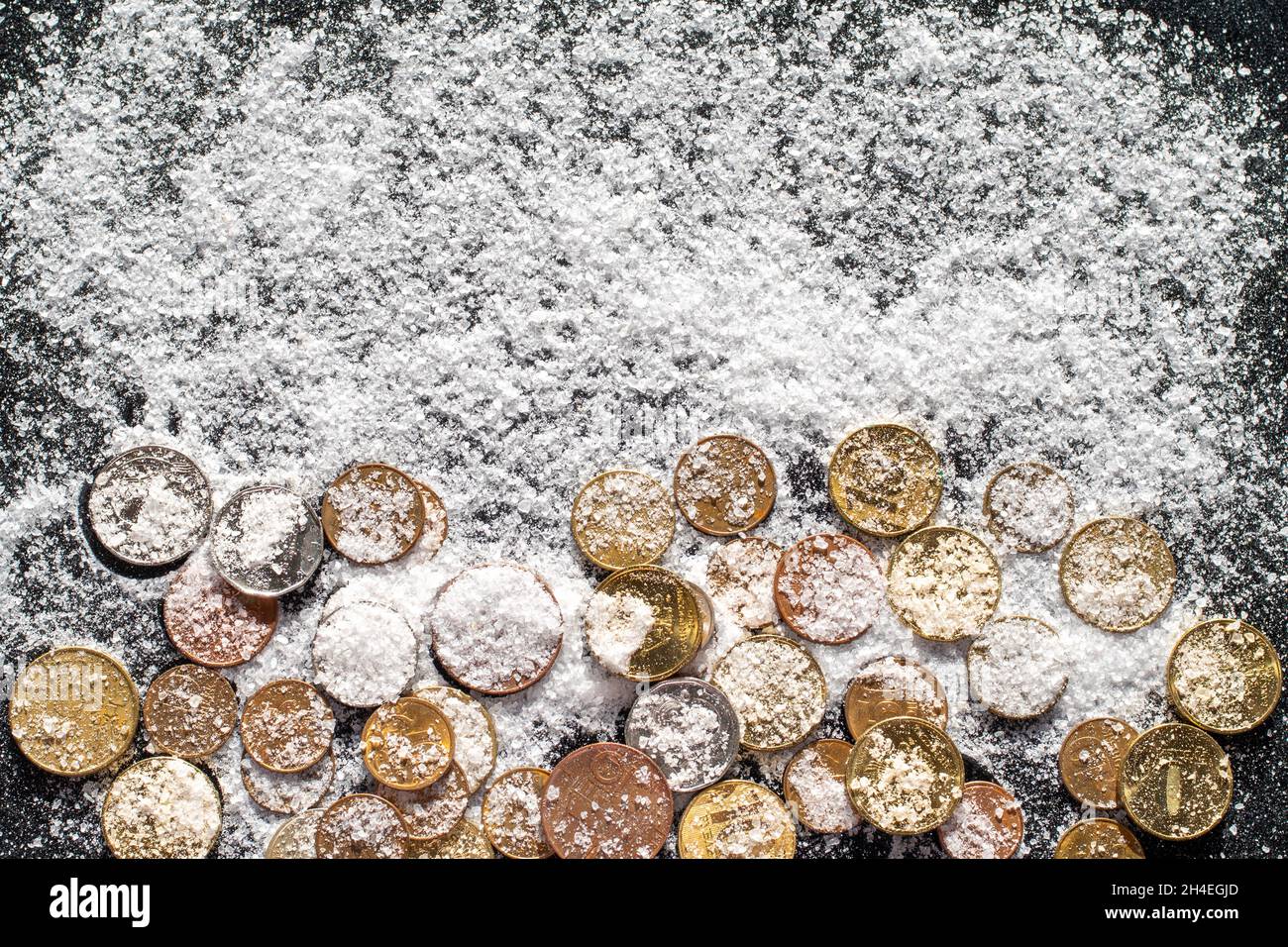 Coins covered with white sea salt such as snow on a black background ...