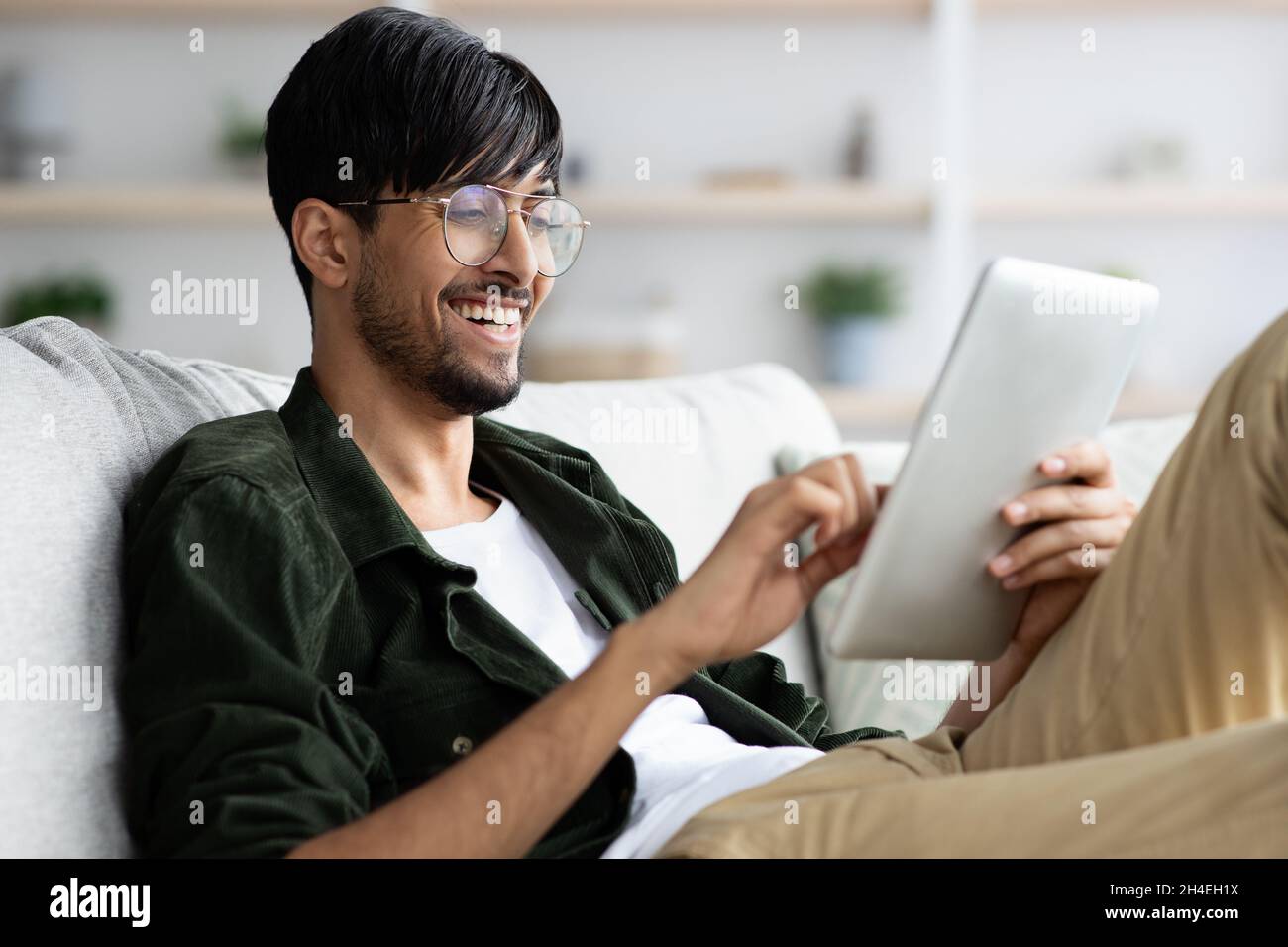 Joyful middle eastern young man chilling at home with tablet Stock ...