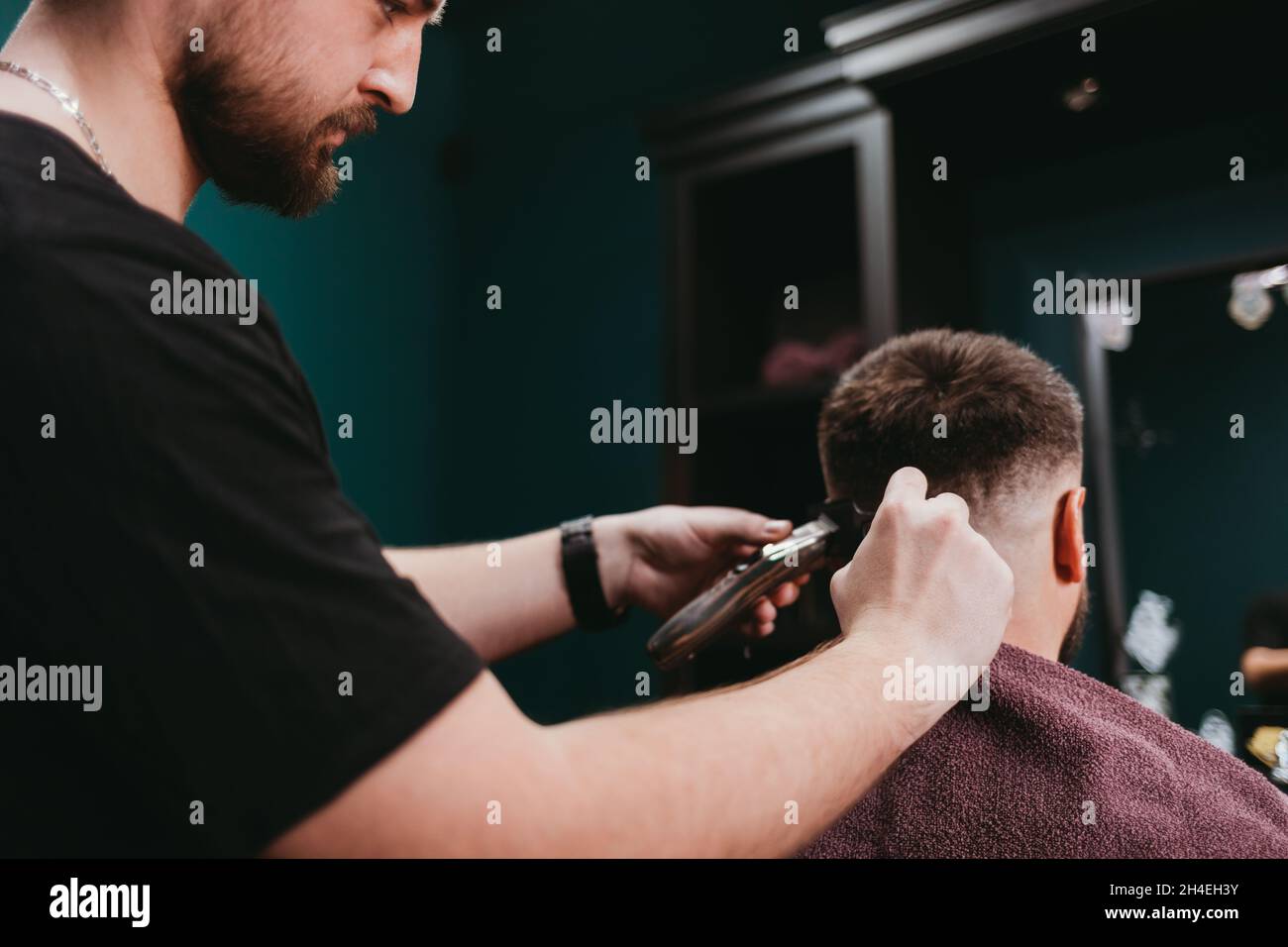 Young guy barber making haircut to client man using clipper in hair ...