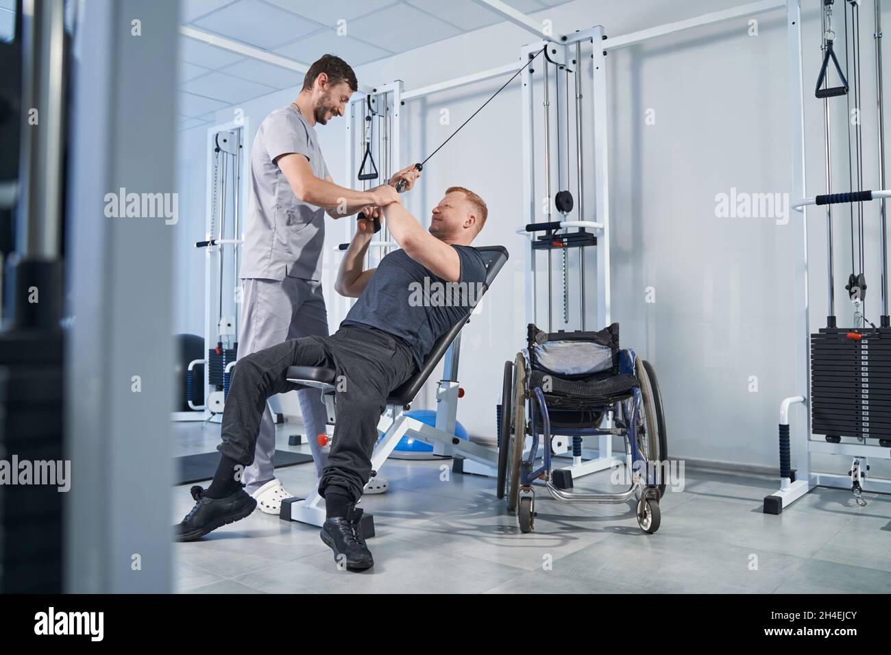 Man with disability pulls stretching strap with help of therapist Stock ...