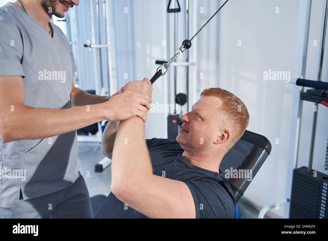 Rehab therapy for patient with handicap. Young man on stretch machine ...