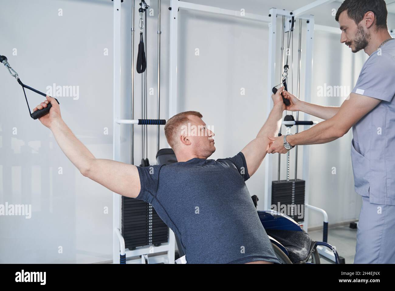 Young man with handicap pull hand with sprain simulator with therapist ...