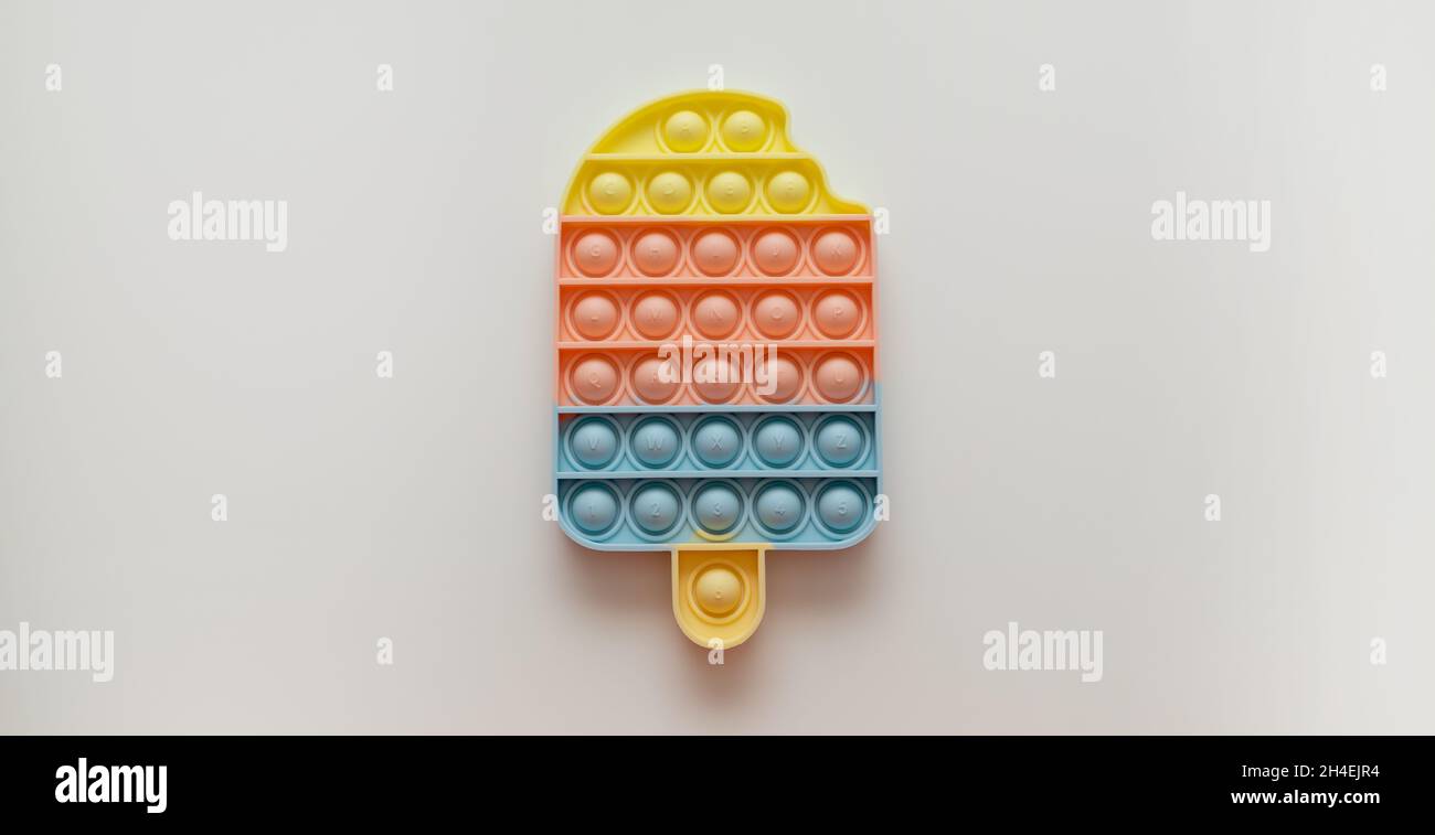 Colorful trendy Pop it fidgets ice cream shape toy on a bright grey ...