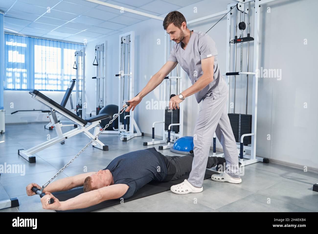 Trainer help young man training on pull cable exercising machine Stock ...