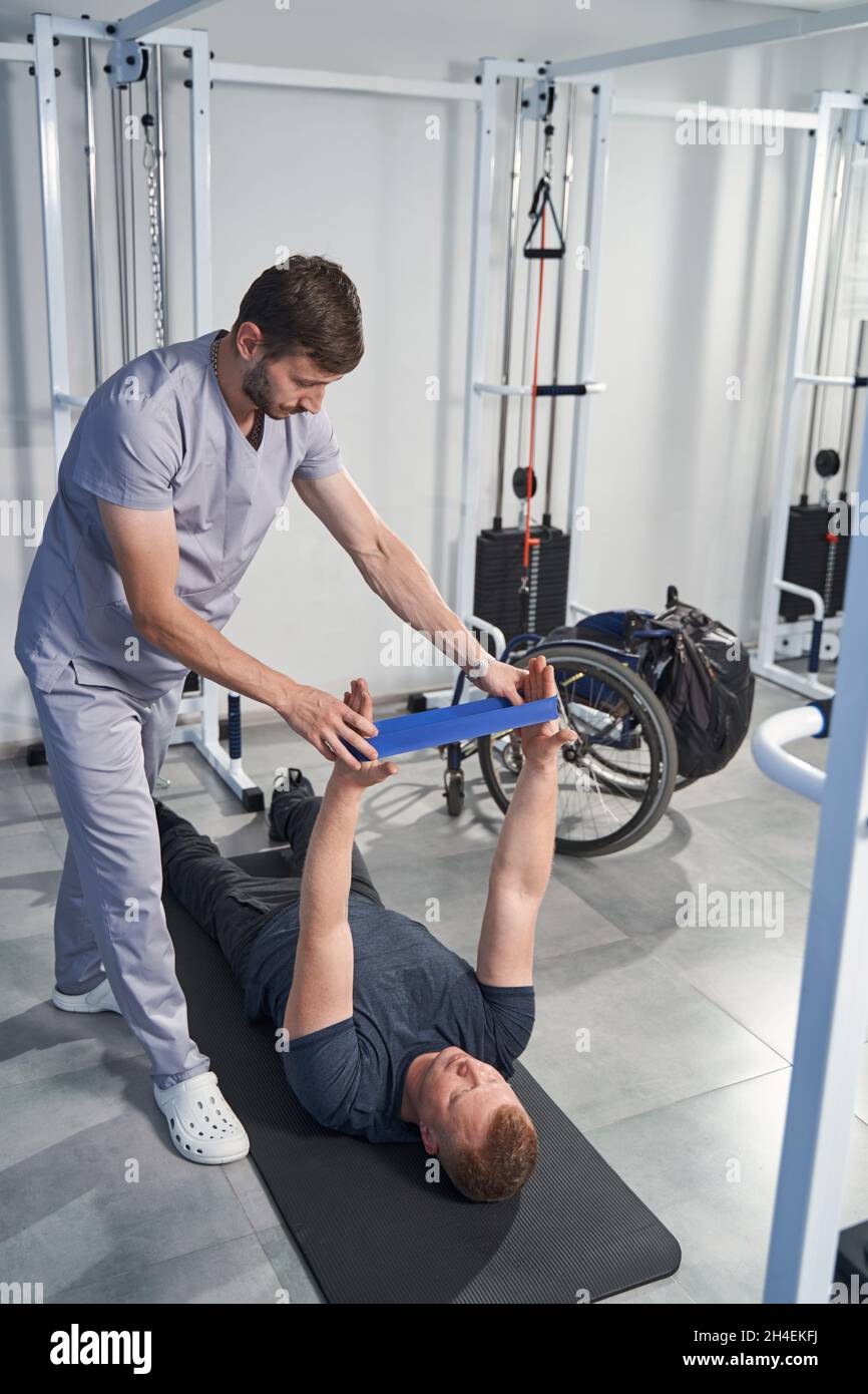 Man with disability exercises strength with rubber resistance band ...