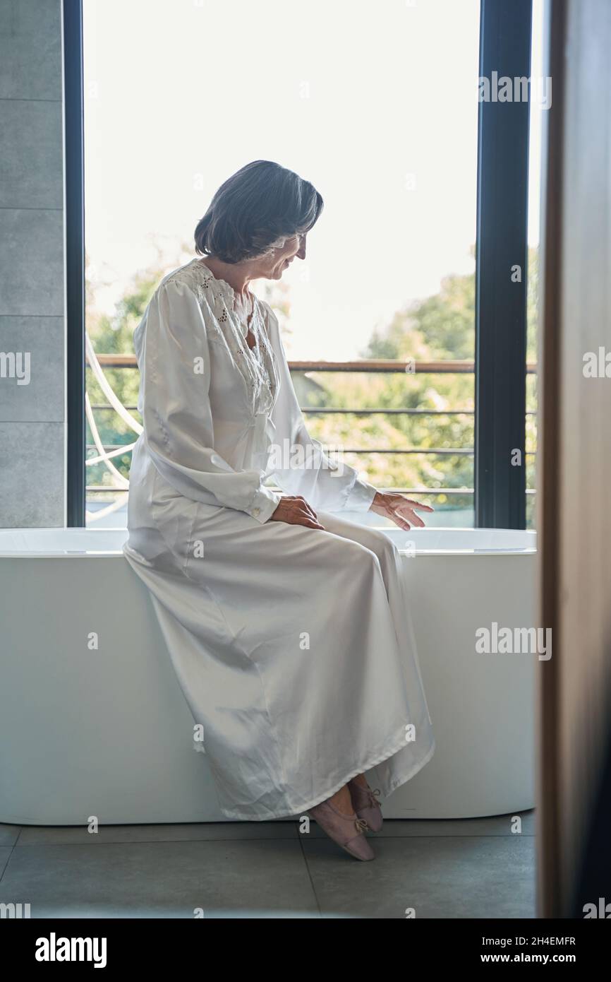 Aging lady checking water temperature in bathtub Stock Photo - Alamy