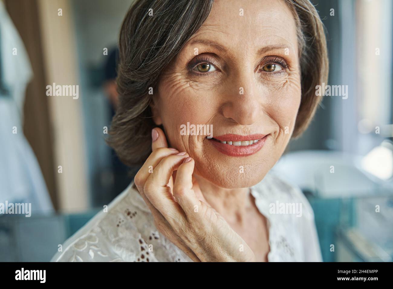 Female pensioner running hand over her cheek Stock Photo - Alamy
