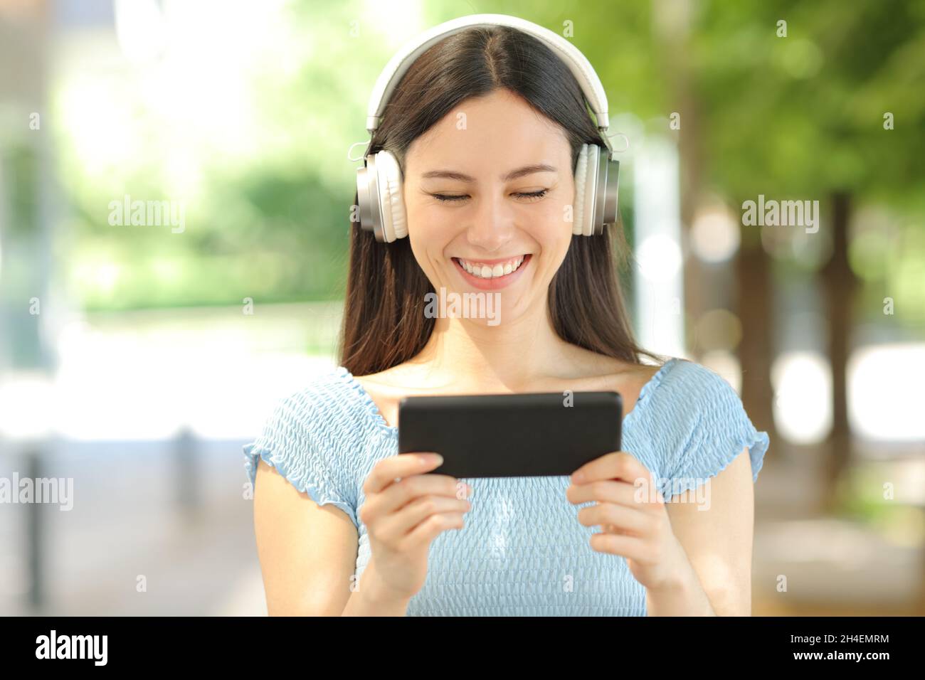 Front view of an asian woman watching videos on smart phone walking in ...