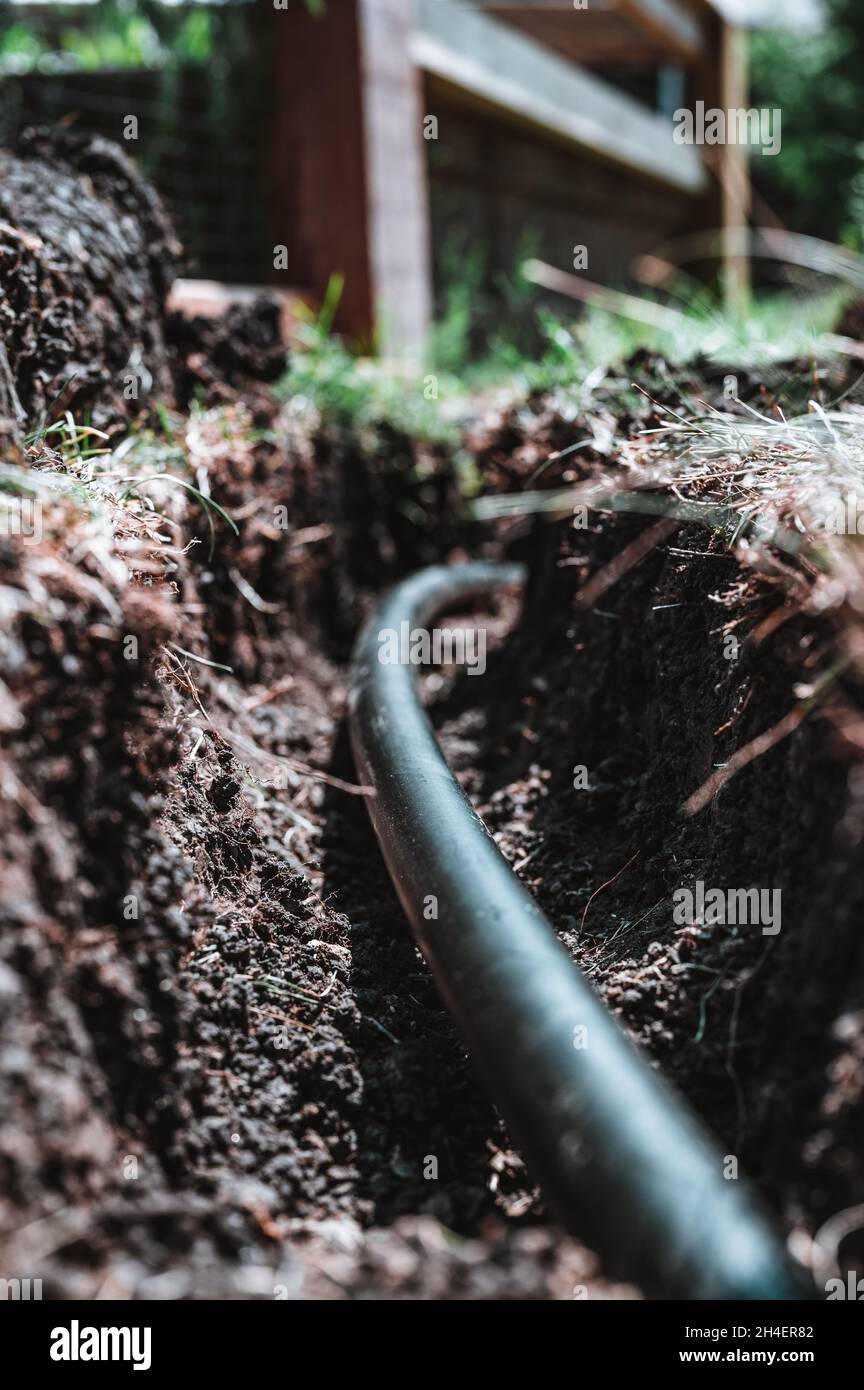 Focus on a black 1 inch sprinkler plastic water line laid in a shallow ...