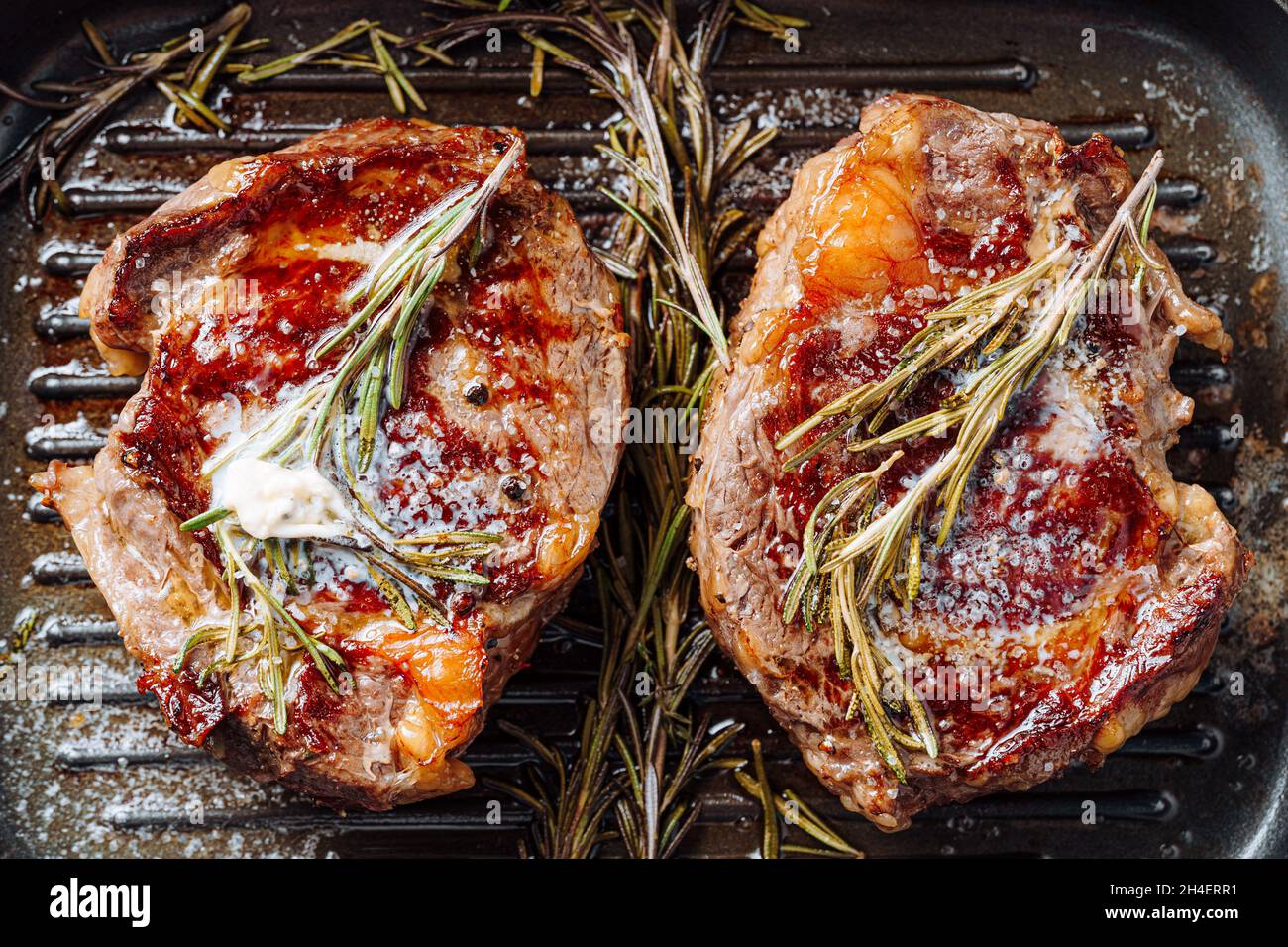 cooking sumptuous steaks in a grill pan with butter spreading over the ...