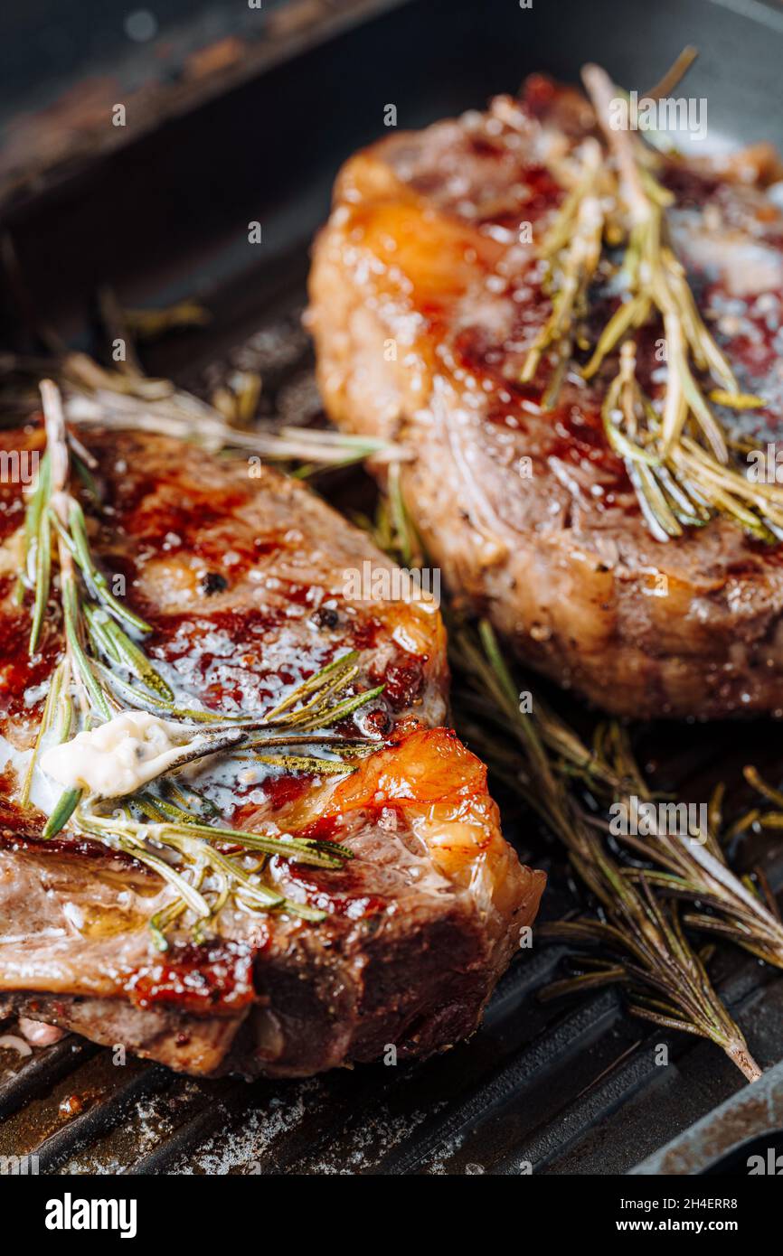 cooking sumptuous steaks in a grill pan with butter spreading over the ...