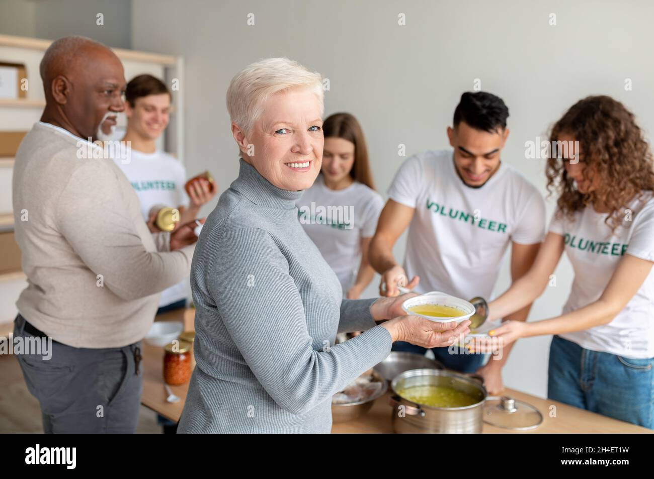 Help for aged people. Volunteer group helping feed senior people with ...