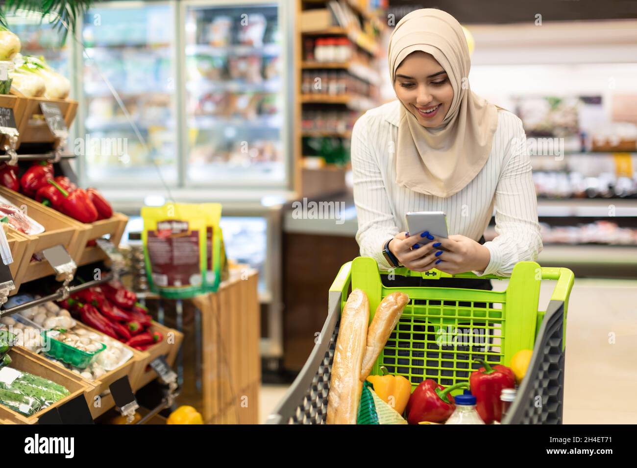 Muslim Woman Using Smartphone Doing Grocery Shopping In Store Stock ...