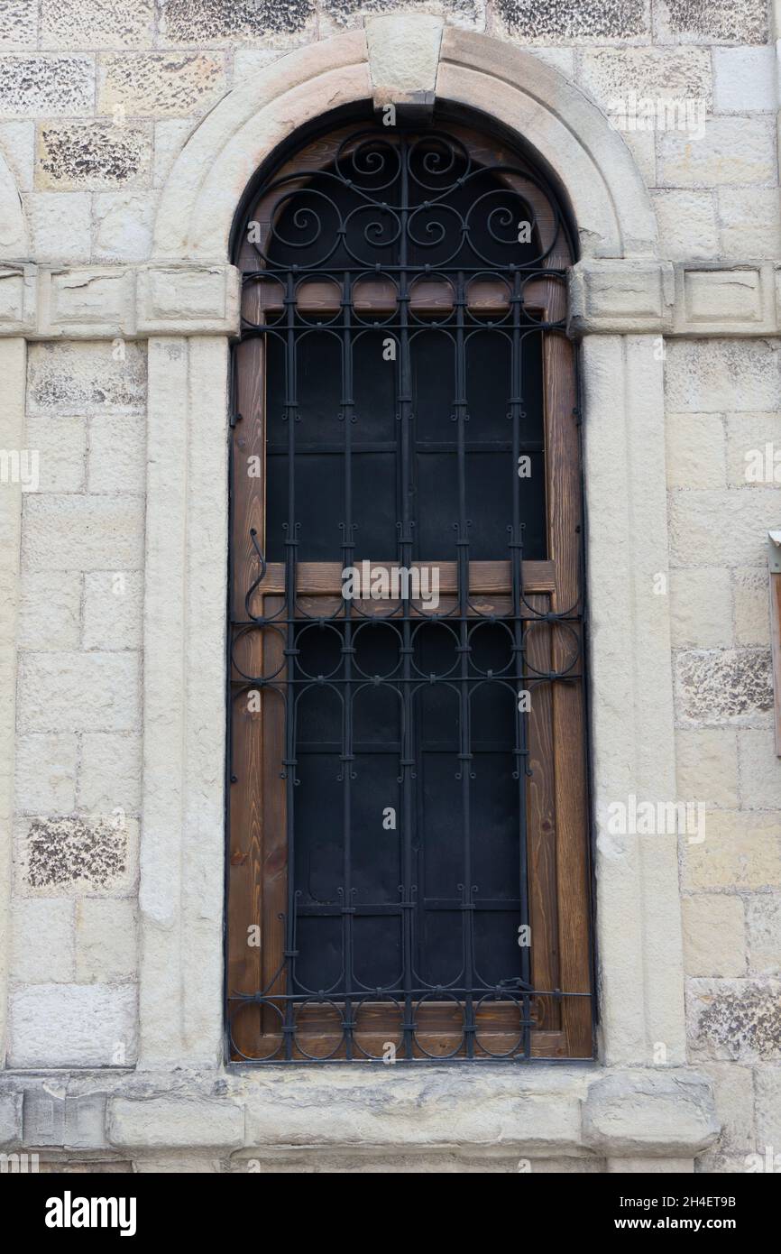 Vertical shot of a radius window behind a black cell on a white wall ...