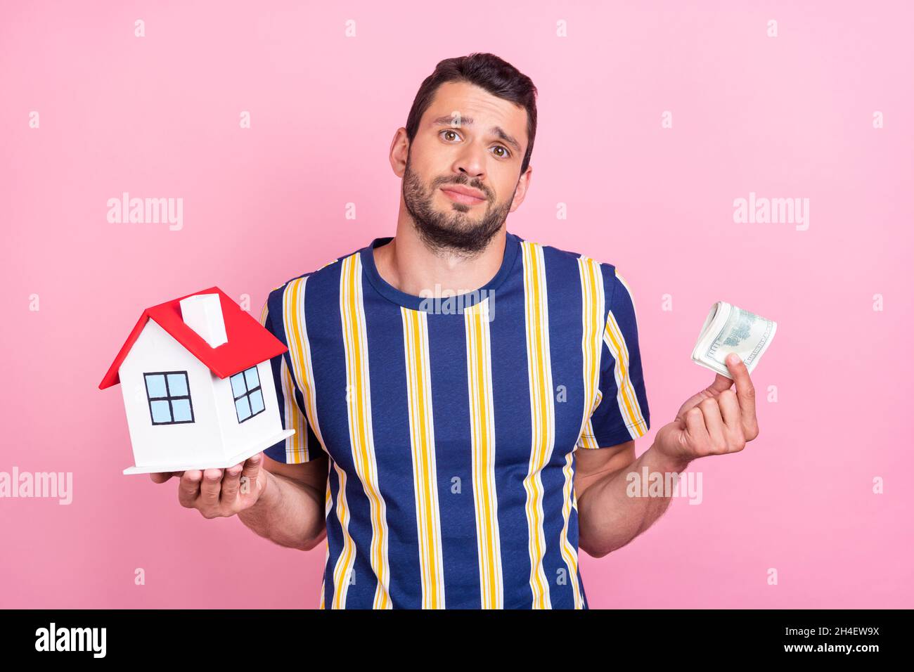 Portrait of attractive hesitant guy holding house figure cash deciding ...