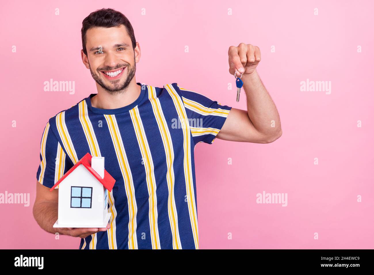 Portrait of attractive cheerful guy holding house figure key bank ...
