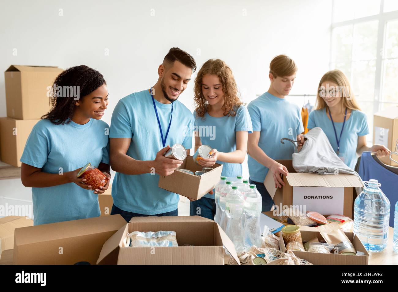 Food sorting. Group of young diverse volunteers packing products and ...