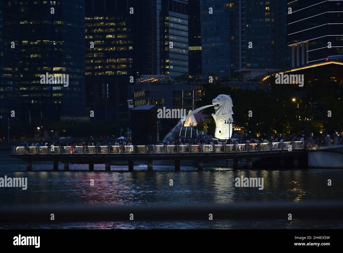 singapore merlion statue glowing on a lake side at night with city ...