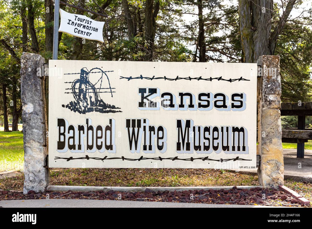The large, white sign for the Barbed Wire Museum held up by large post ...