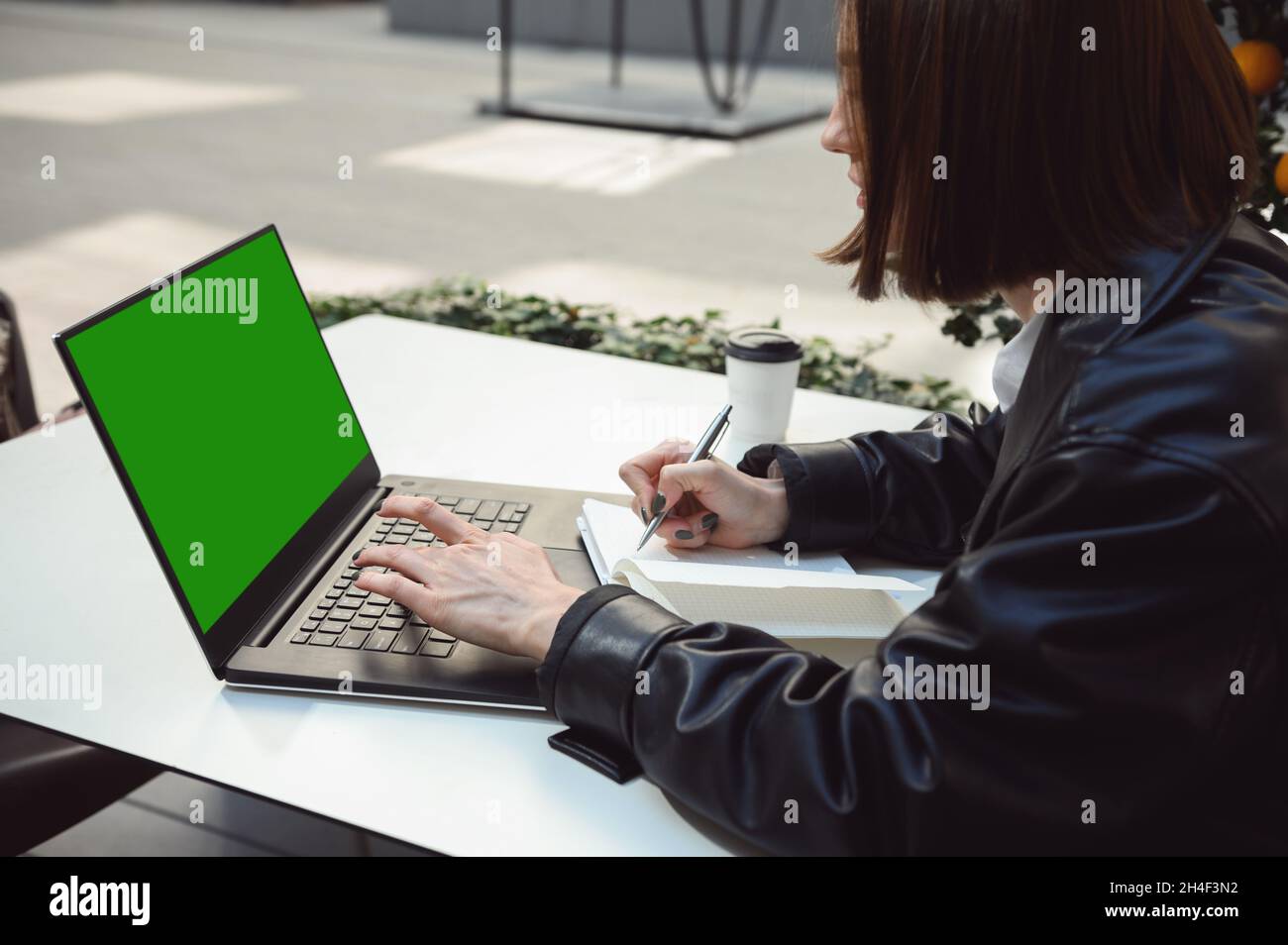 Side view of a woman freelancer, copywriter, writing texts on notepad ...