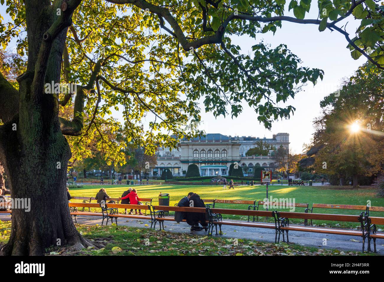 Wien, Vienna: park Stadtpark, people at benches enjoy last sunshine of the day, autumn colors ...