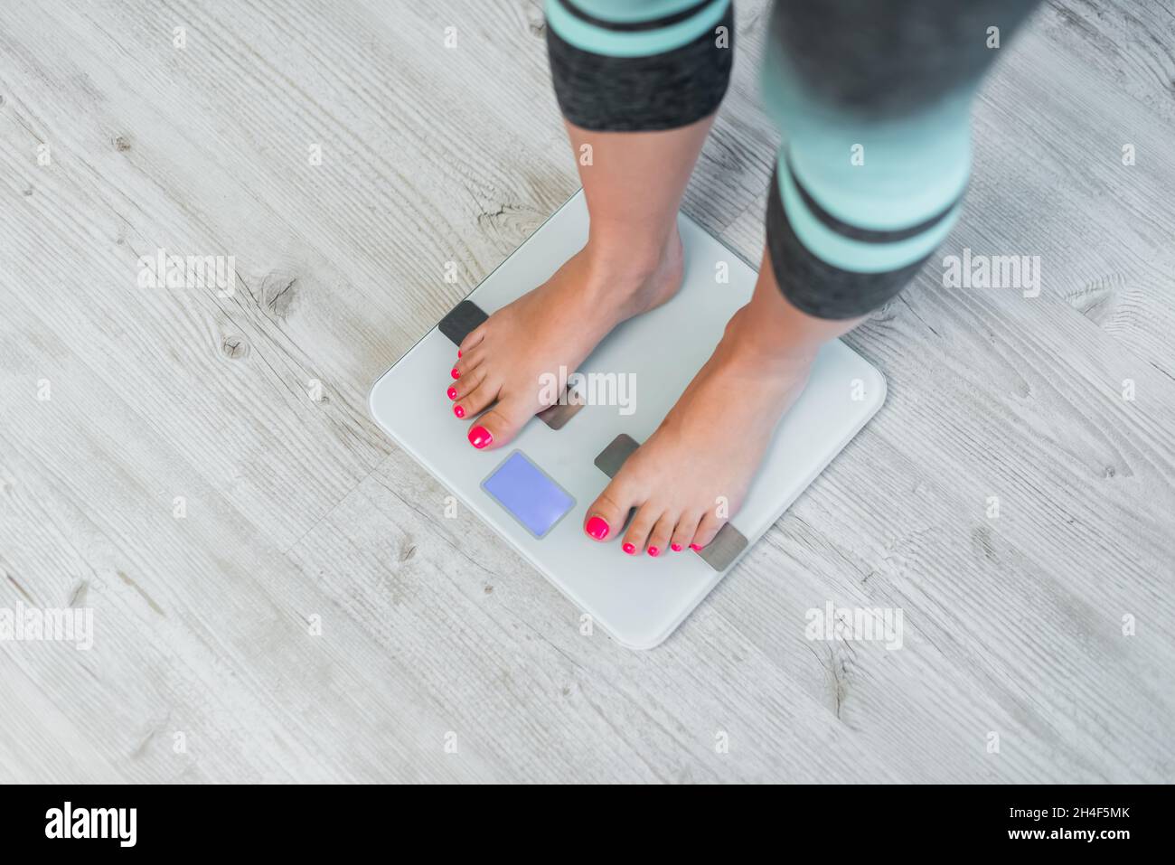 partial view of barefoot woman measuring body weight on floor scales ...