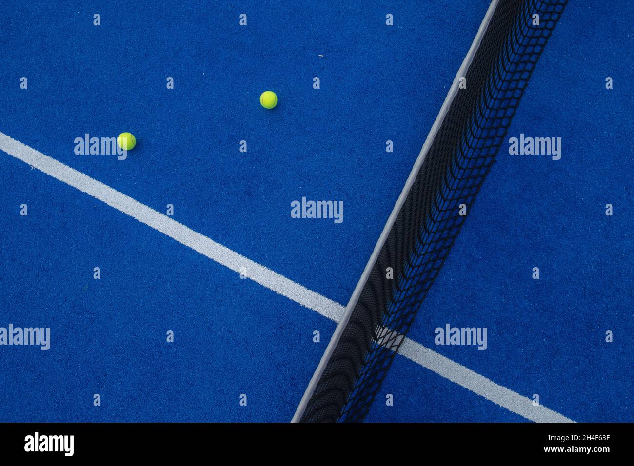 Two balls next to the service line and the net of a paddle tennis court ...