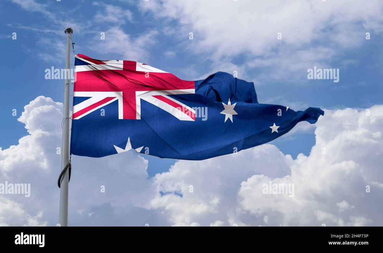 Flag of Australia at a flagpole moving in the wind against the sky ...