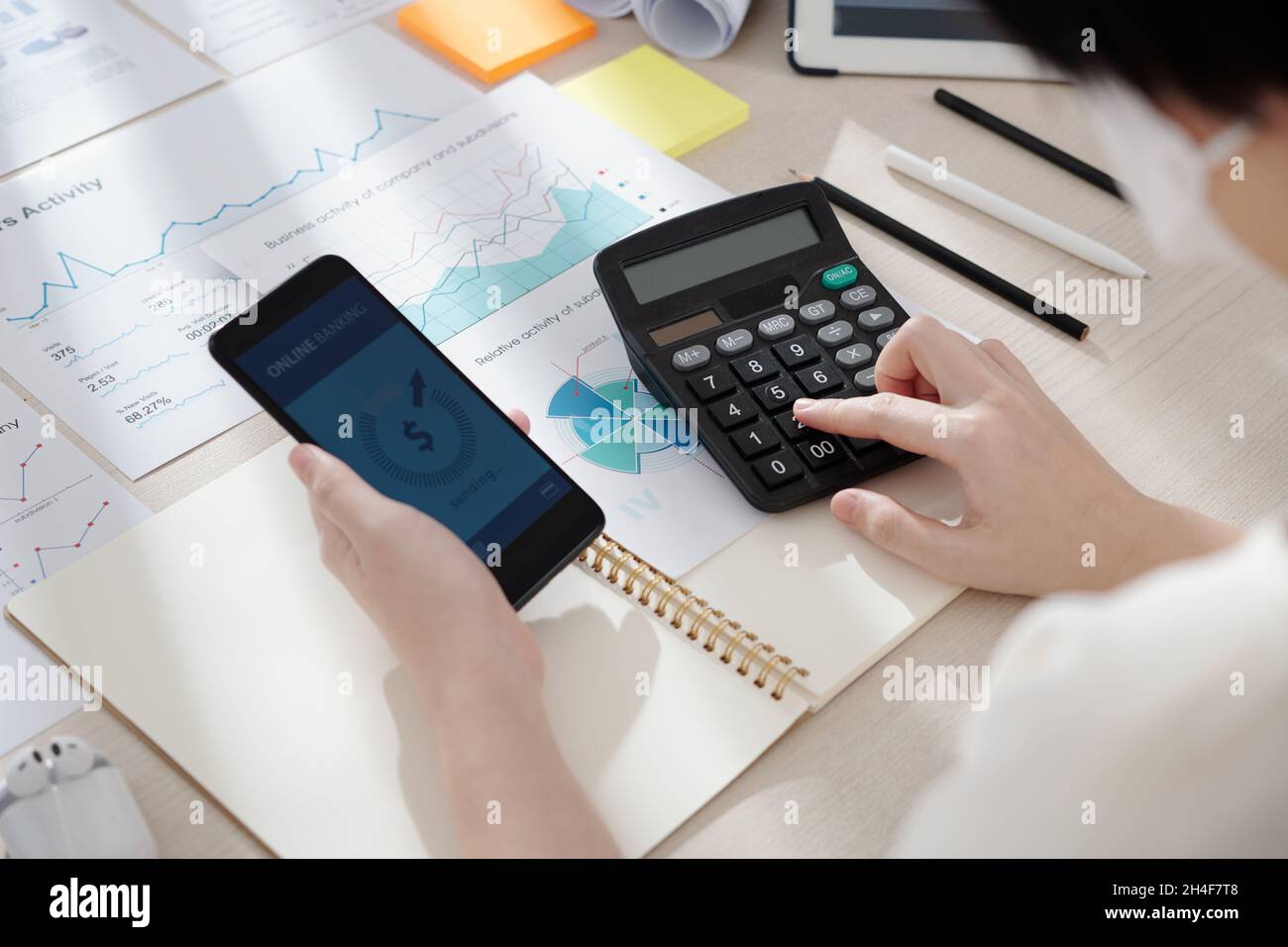 Hands of person making calculation when using online banking ...