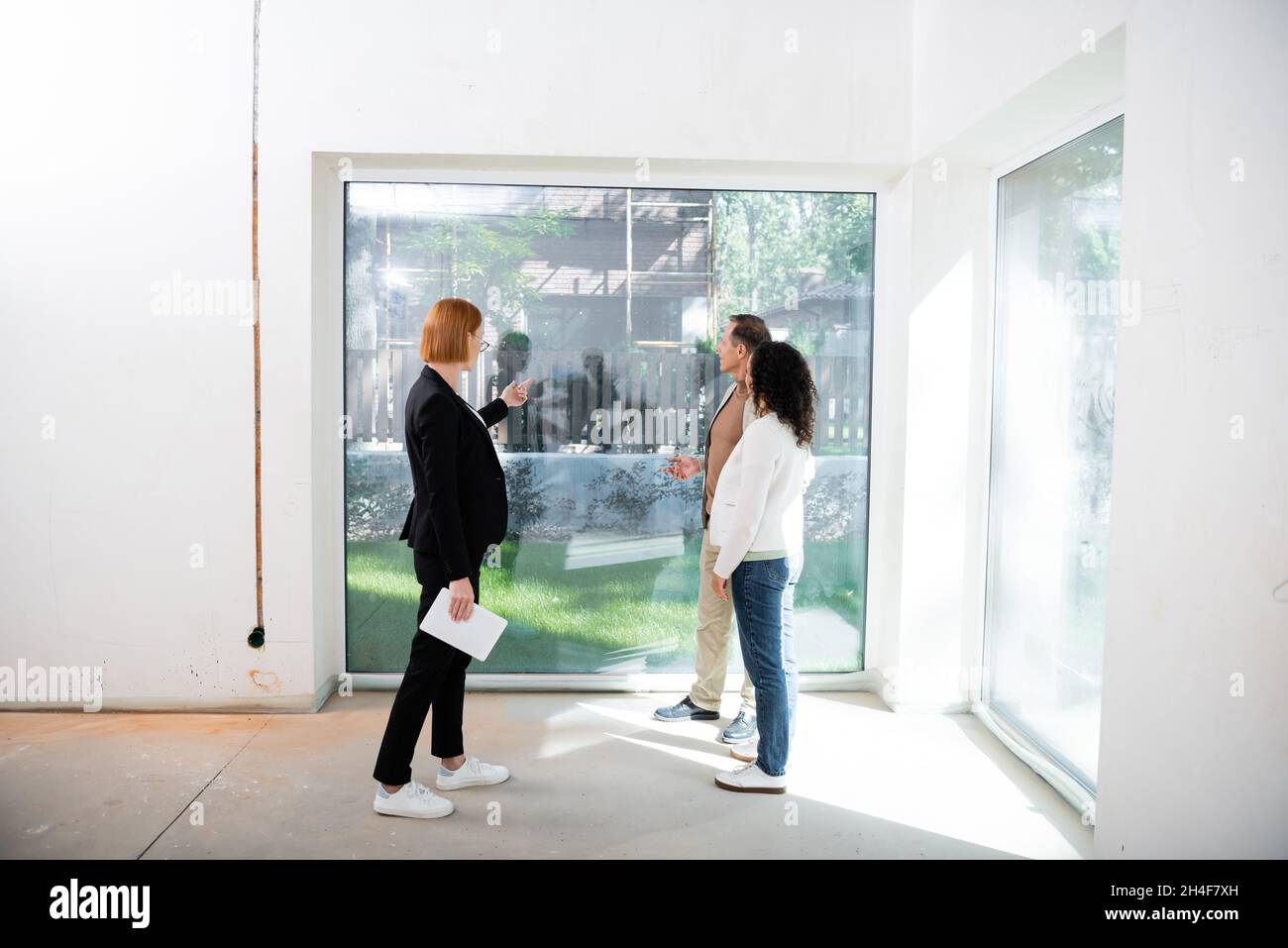 redhead realtor in glasses holding digital tablet while pointing at ...