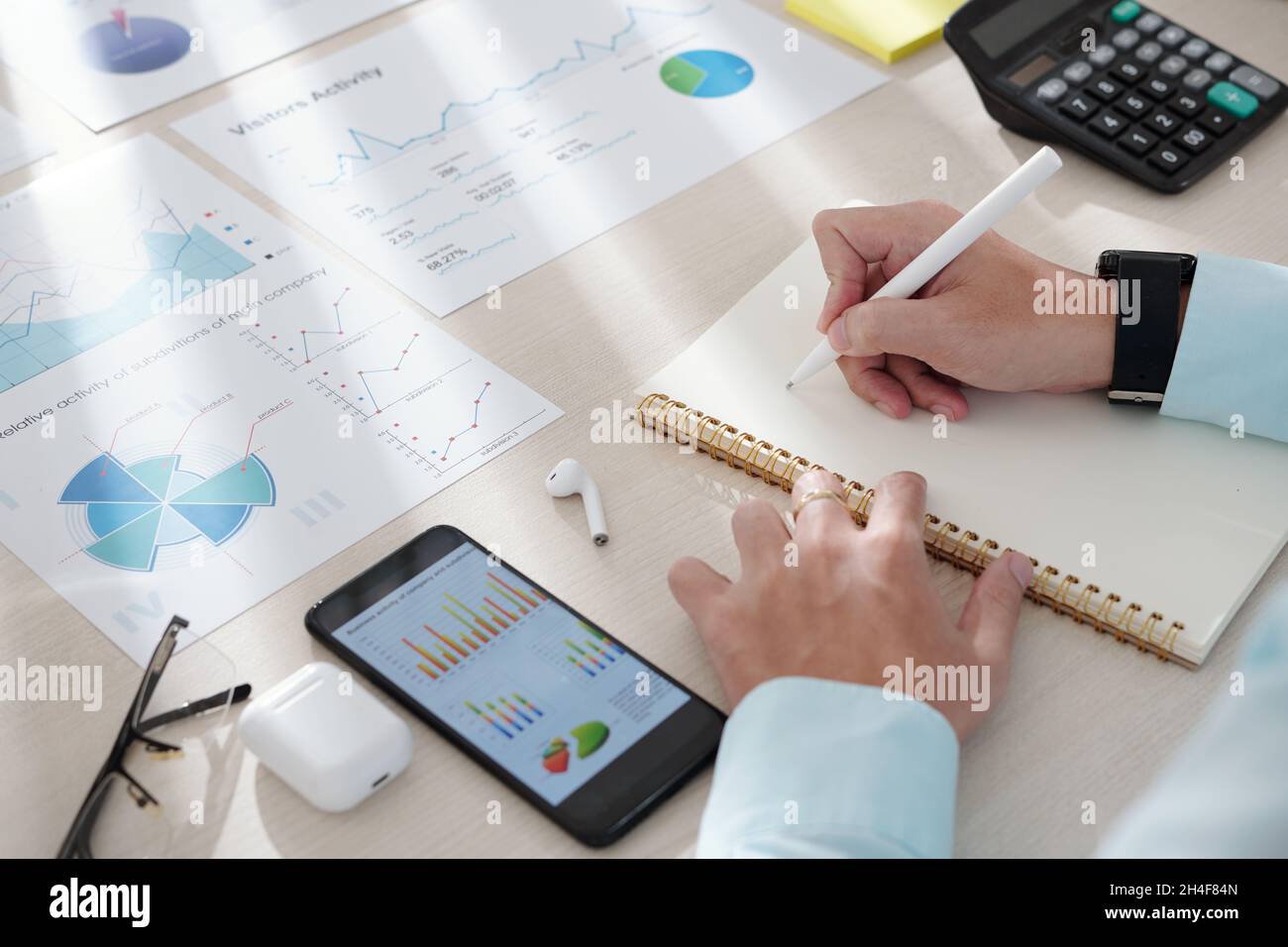 Hands of business person taking notes when working with charts on ...