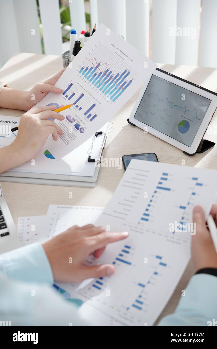 Business colleagues discussing data in charts and reports when working ...