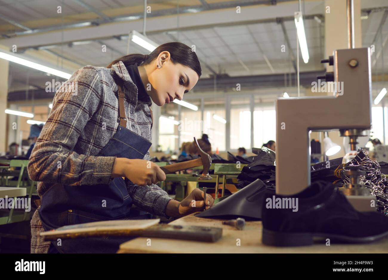 Worker using hammer and nail while making new leather boots at shoe ...