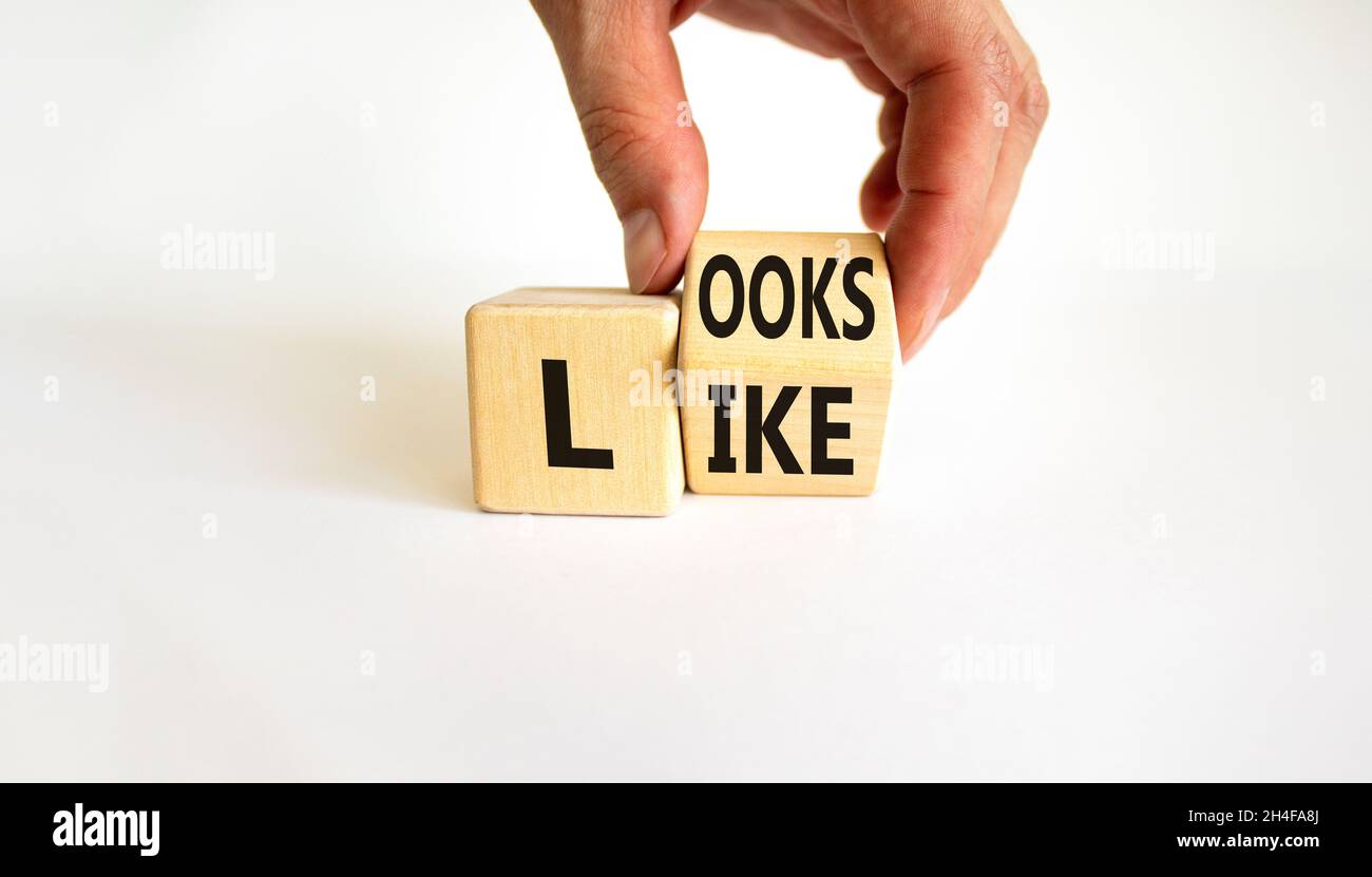 Looks like symbol. Businessman turns a wooden cube with words 'Looks ...