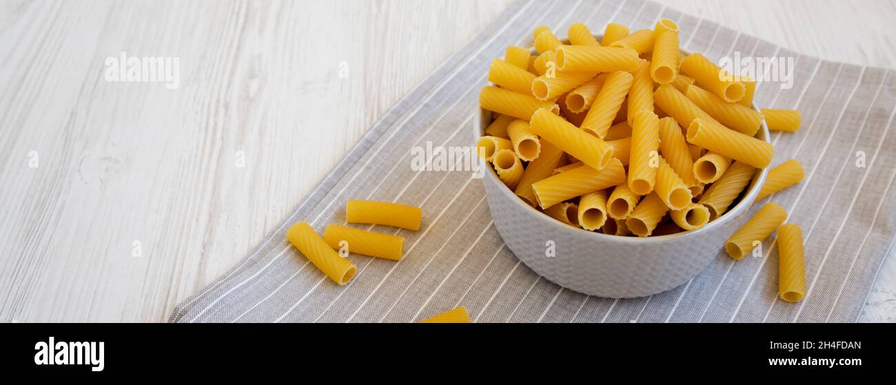 Dry Rigatoni Pasta in a gray Bowl on a white wooden background, low ...
