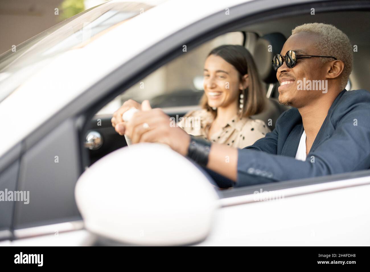 Happy multiracial couple driving at car together Stock Photo - Alamy