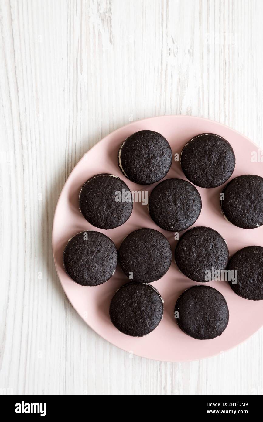 Homemade Oreos on a pink plate on a white wooden background, top view ...